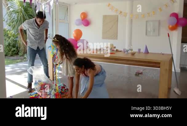 Family preparing birthday celebration at home with colorful streamers ...