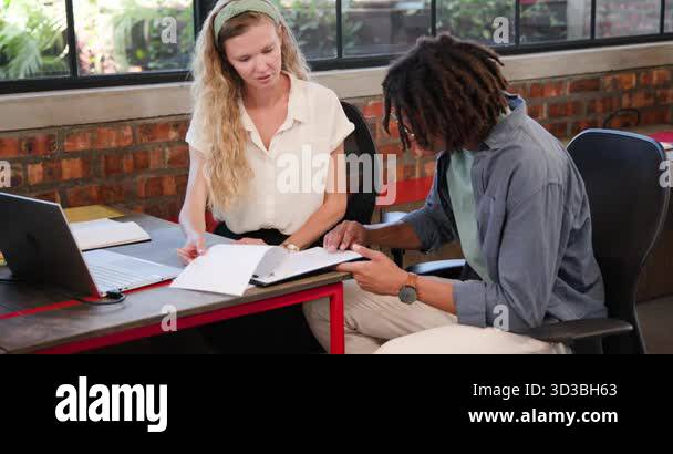 After man's gesture, diverse colleagues reviewing binder, signing form ...