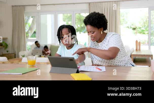 African American family engaging in learning together at home table ...