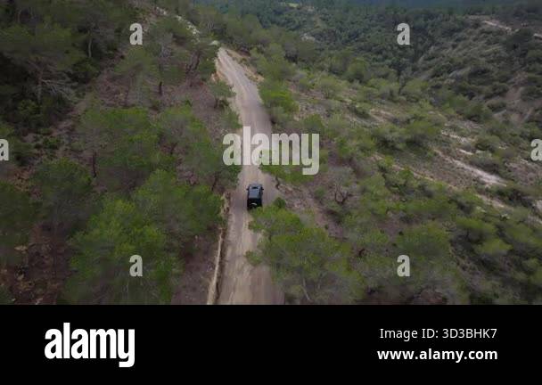 Aerial shot of dark off road vehicle driving on winding dirt track ...