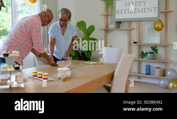 Noticing party banner in dining room, diverse seniors arranging table ...
