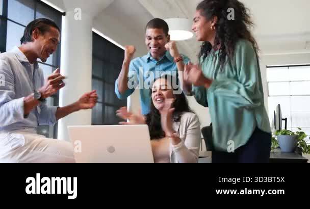 Happy diverse colleagues discussing work around laptop and celebrating ...