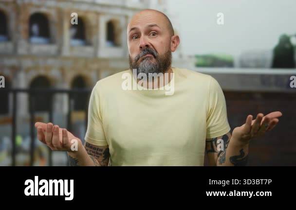 Bald man with beard looking confused in front of roman coliseum ...
