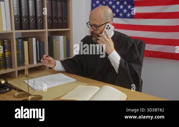 Hispanic male judge with a beard taking notes while talking on a phone ...