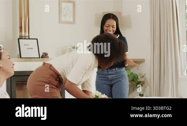 Following graduation, diverse female friends pouring juice and raising ...