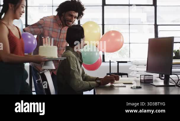 Happy diverse colleagues working and making surprise with balloons in ...