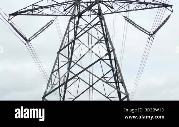 Upward view of electric pylon against cloudy sky, towering steel ...