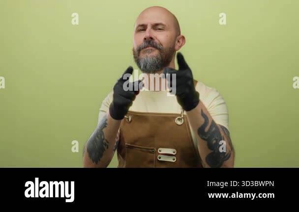 Bald man with beard winking and pointing with gloved hands against a ...