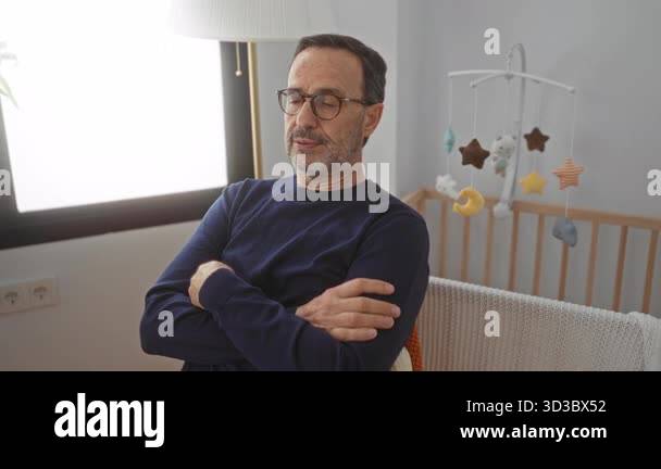 Man experiencing fatigue indoors seated beside baby crib in bedroom ...