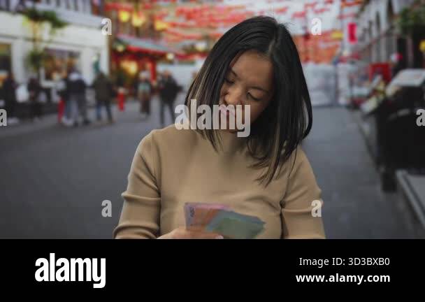 Woman counting chinese yuan banknotes on a bustling city street ...