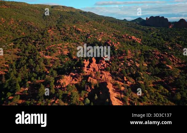 Bright sun lights the red clay rocks covered with greenery. Drone ...