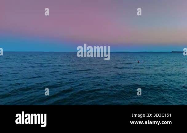 Quickly moving over the blue waterscape at sunset. Beautiful pink blue ...