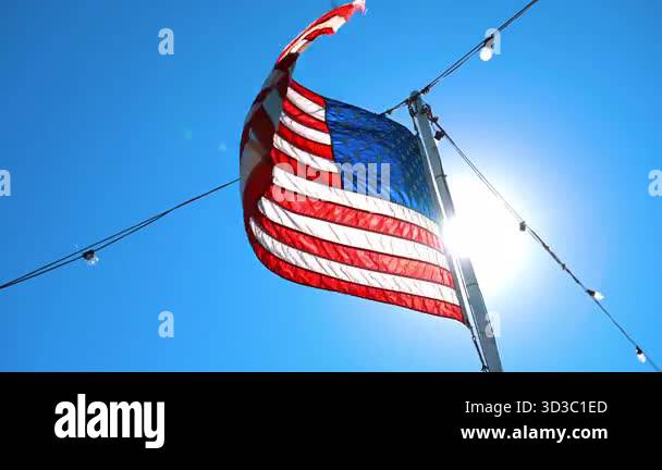 American flag on the mast flapping in the wind. Low angle view. Sun in ...