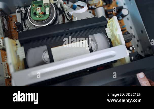 VHS cassette recorder inside the player. Close up. Finger presses the ...