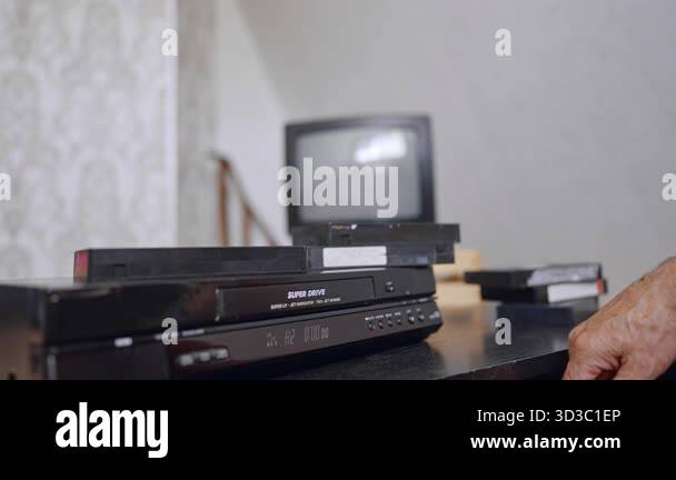 Old-style VHS player on the desk. Male hand presses the button on the ...