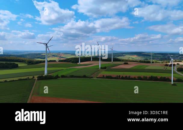 Aerial view of large wind turbines across summer countryside fields ...