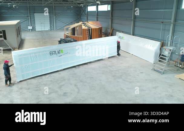 Valka, Latvia - October 29, 2025: Two workers are moving large plastic ...