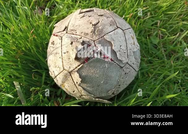 A torn old ball on green grass. The concept of a spoiled old toy. Stock ...