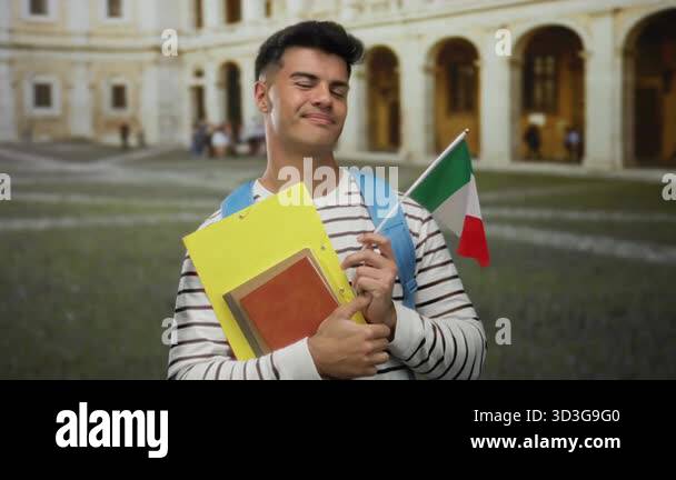 Italian student man smiles holding, books and italian flag in historic ...