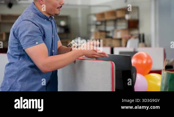 Young man typing on computer at cubicle in modern office with colorful ...