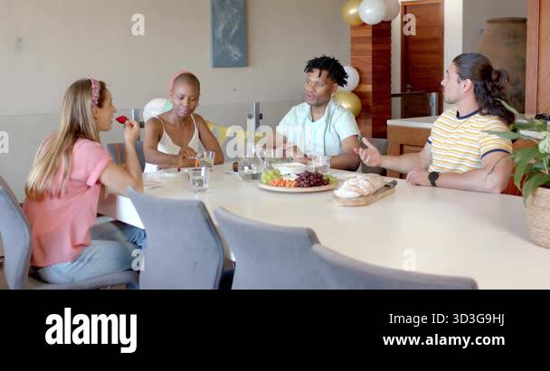 Friends enjoying casual conversation around dining table with snacks ...