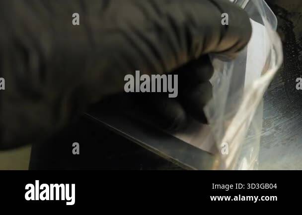 Police investigator in black gloves packing seized illegal LSD drugs ...