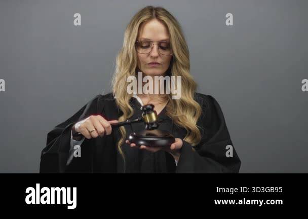 Woman judge with blonde hair in a black robe holding a gavel against a ...
