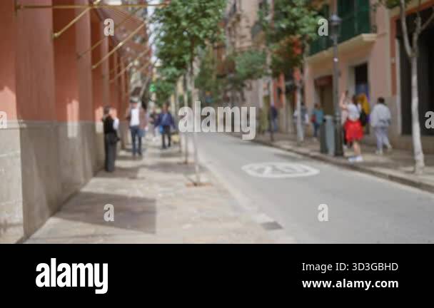 Blurry street scene in a european town with people, trees, and colorful ...