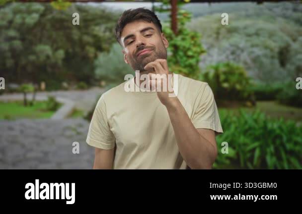 Man touches chin with hand on chin gesture in lush green forest under ...