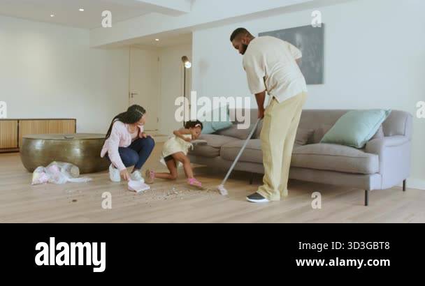 Diverse family cleaning up modern living room after celebration, using ...