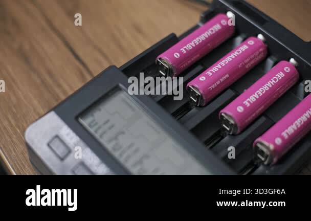 Close up of four pink rechargeable AA batteries in a black charging ...