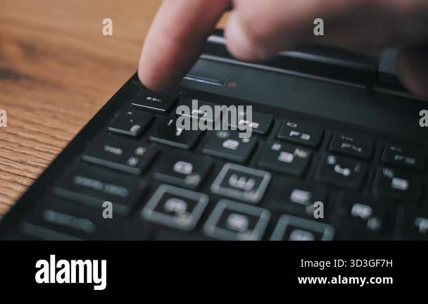 Closeup of a finger pressing the escape key on a black laptop keyboard ...