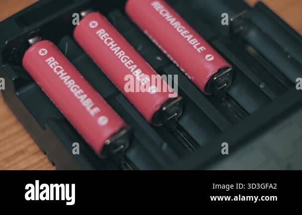 High angle view of a hand removing four rechargeable AA batteries one ...