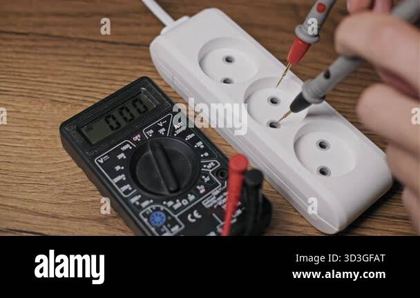 Closeup of an electricians hands using digital multimeter probes to ...