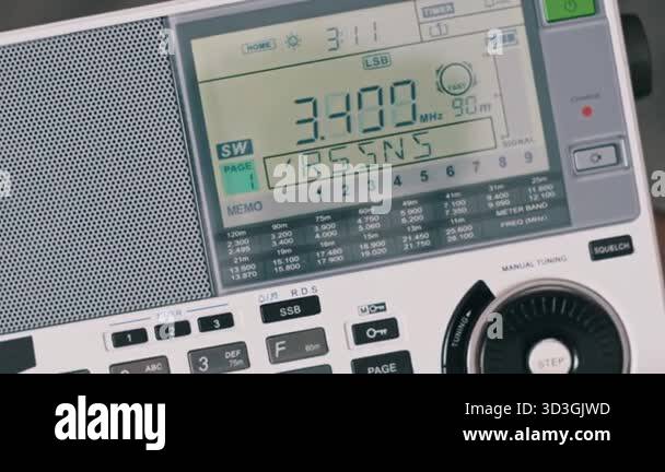 Top-down view of a person tuning a portable shortwave radio. A finger ...