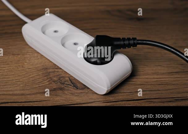 Closeup of a male hand unplugging a black power cord from a white ...