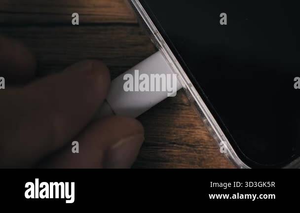 Angled closeup of a hand unplugging a white USB-C power cord from a ...