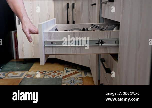 Person opening and closing wooden kitchen drawer with utensils inside ...