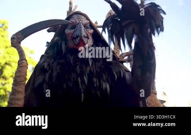 Frightening Halloween reaper figure with black feathers, dark robe, and ...