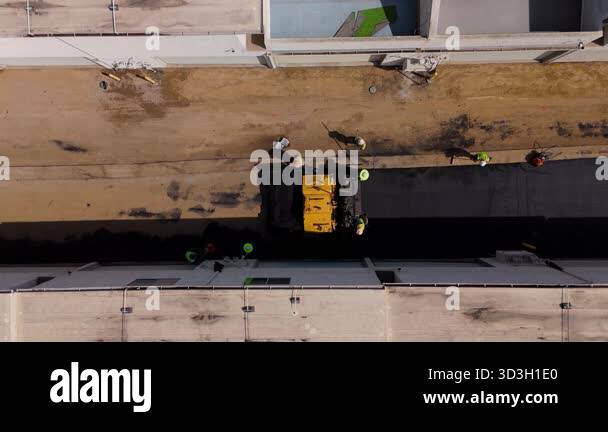 Aerial top down view of construction workers paving a new asphalt road ...