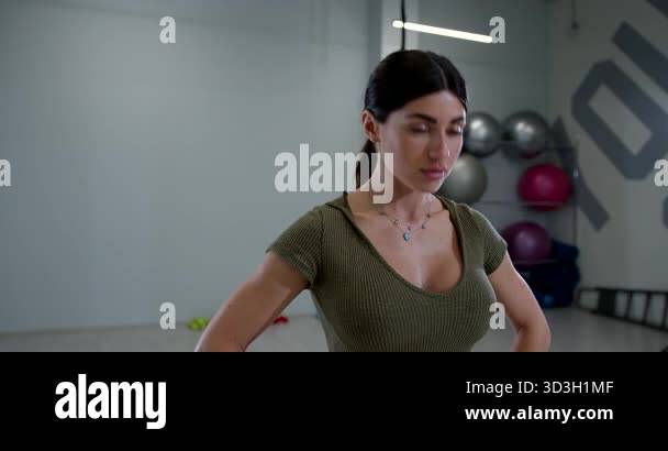 In a fitness studio environment an athletic woman bends her head ...