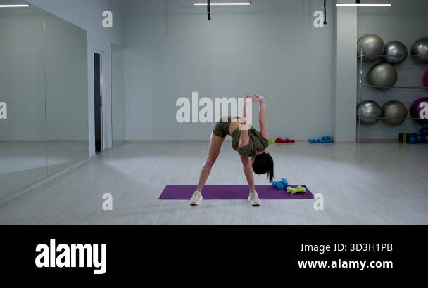 athletic woman is engaged in a Forward Bend pose with her hands clasped ...