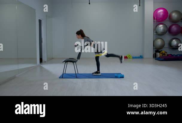 athletic woman is engaged in a bent over glute kickback while using a ...
