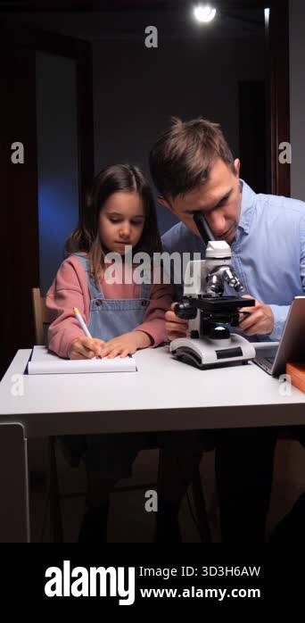 vertical video Father and daughter using a microscope for a science ...