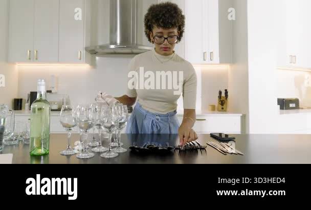Female wiping wine glasses with cloth, arranging cutlery, answering ...