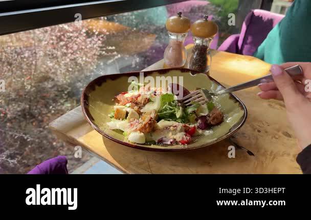 Caesar salad on a wooden table by the window with salt and pepper ...