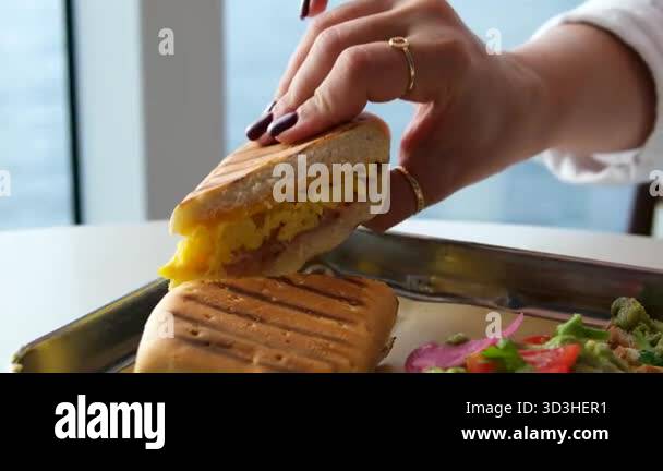 Close up shot of hand of female grabbing sandwich from plate. Young ...