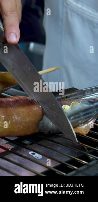 Grilled stuffed squid cutting board: hands in a black glove cut a ...