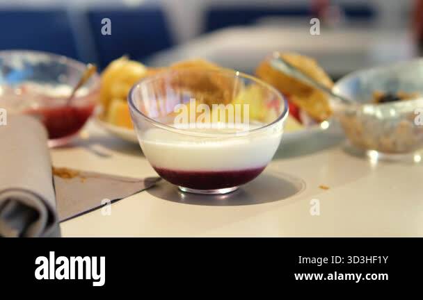 A person uses a spoon to mix and scoop cendol dessert in a ceramic bowl ...