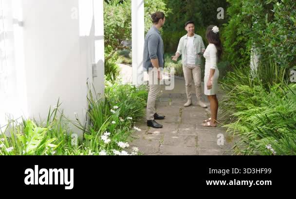 Friends greeting on garden walkway, exchanging gift boxes to celebrate ...
